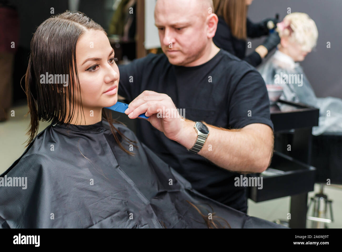 Hair stylist is making new hairstyle for beautiful young woman in hair ...