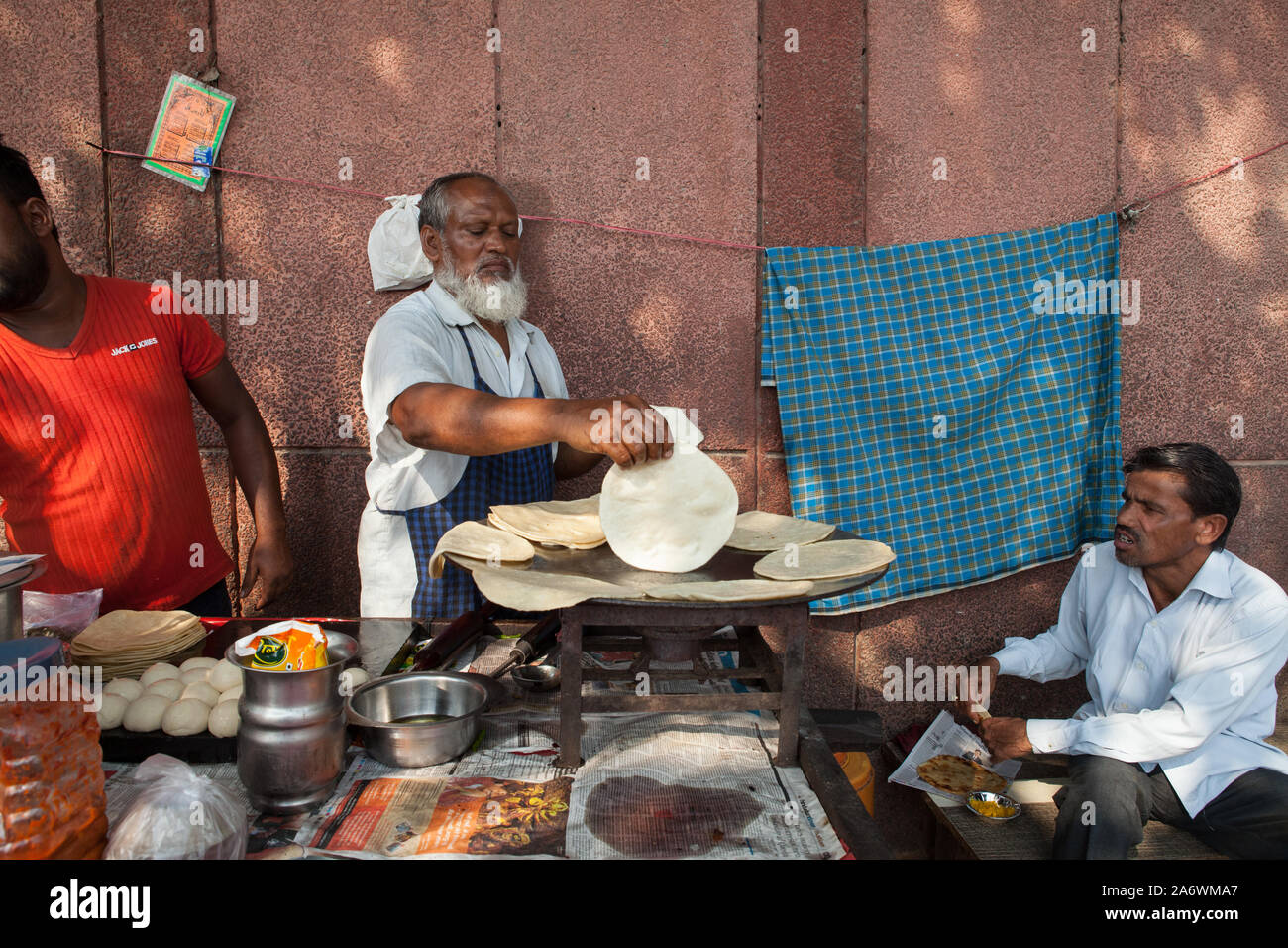A street vendor cooks chapatis at his food stall in the old city of ...