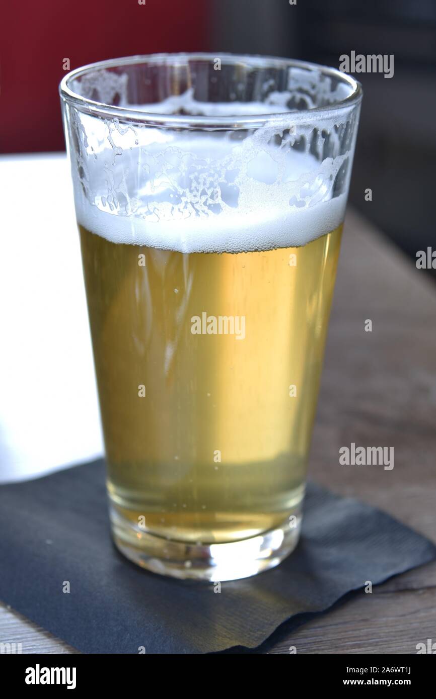 Glass of beer on a table, pint of lager Stock Photo - Alamy