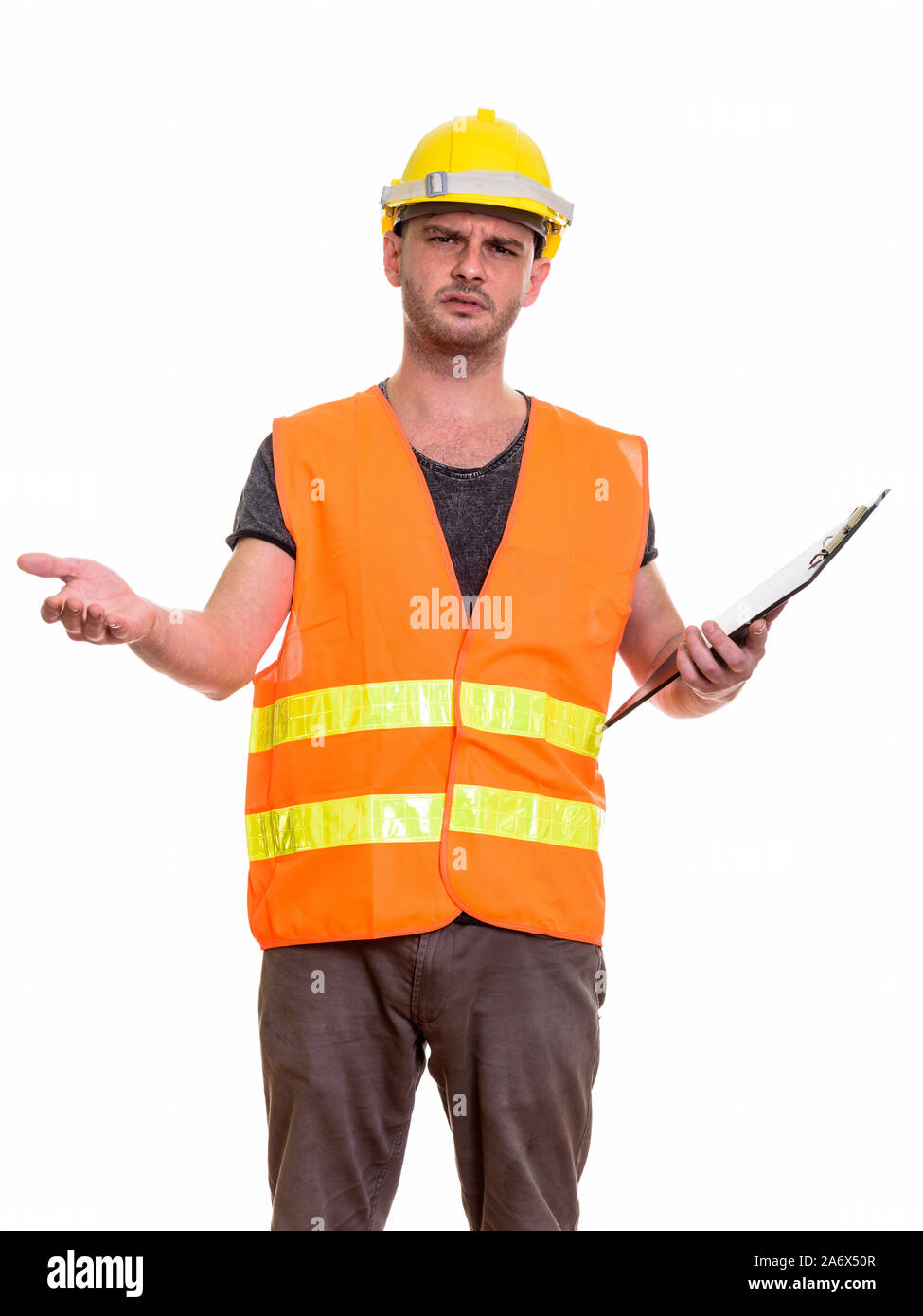 Angry young man construction worker looking confused while holdi Stock ...