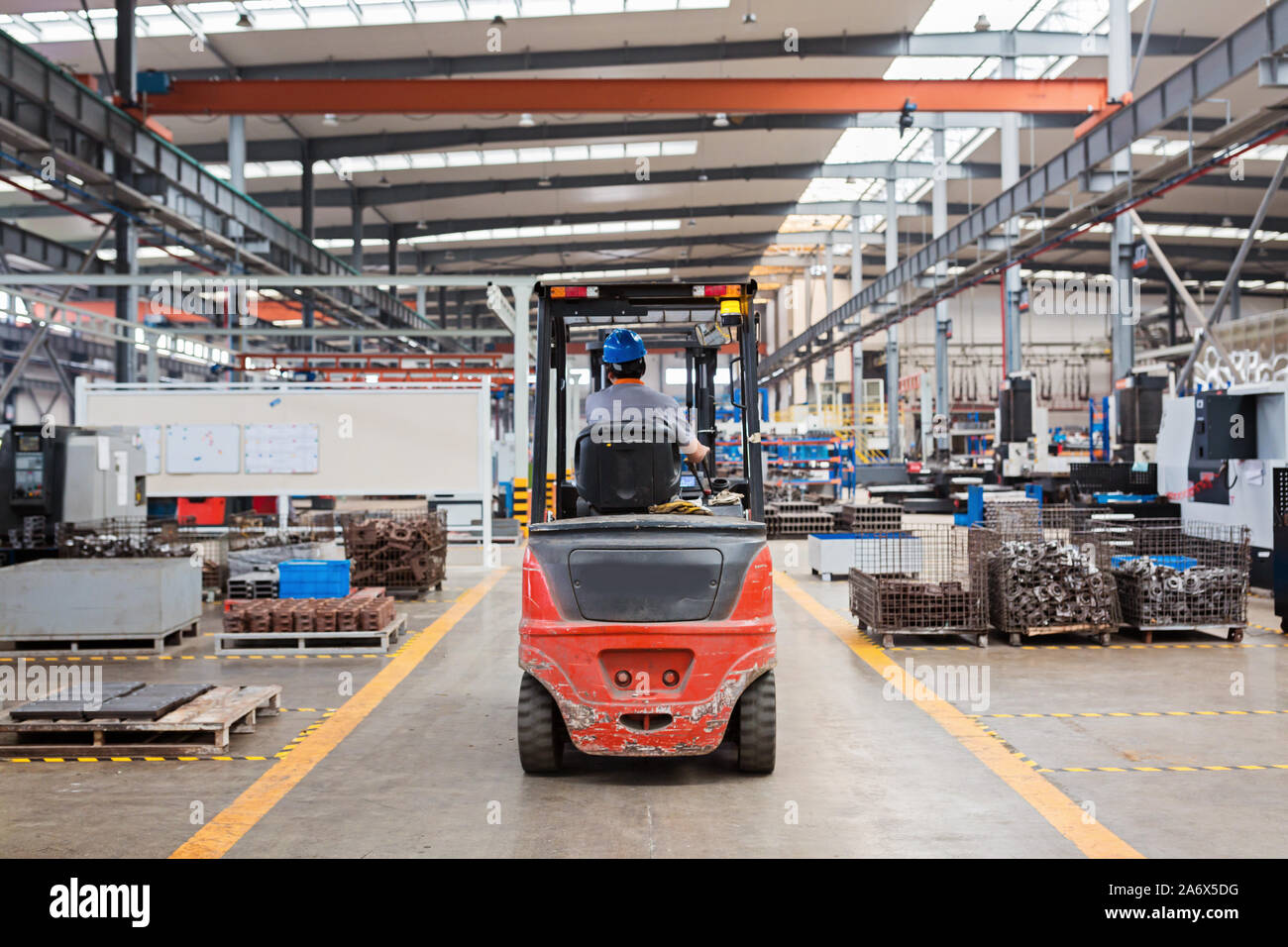 Employee working on forklift in modern warehouse. Boxes are on the ...