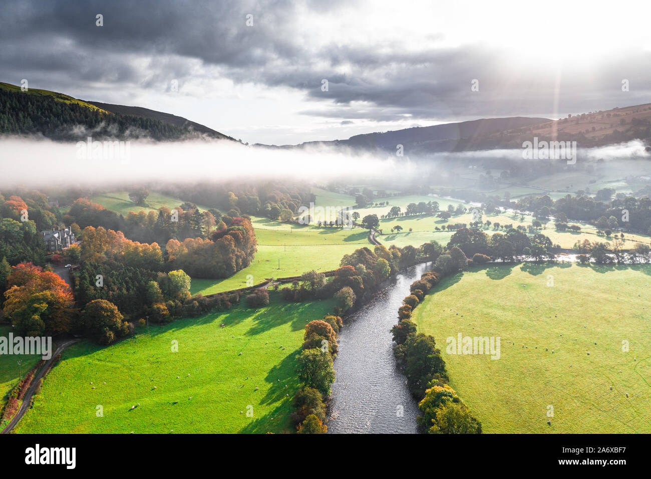 Aerial shoot through misty patches over scenic river valley at autumn ...