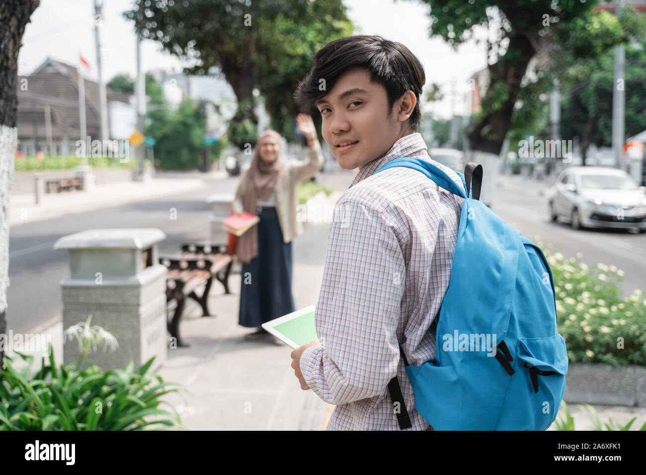 portrait of teenage student smiling and say hello to her friend when ...