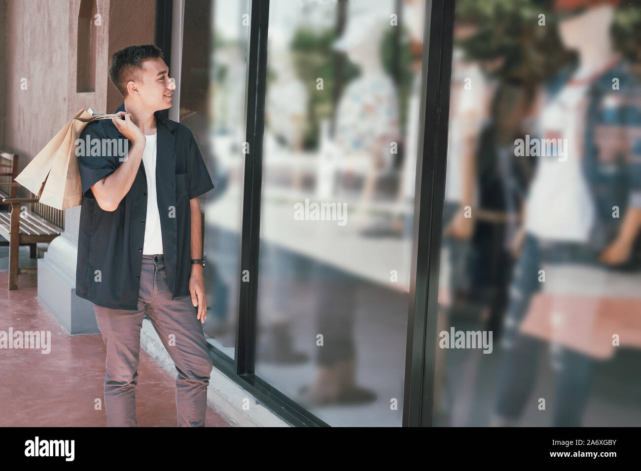 man holding shopping bags looking at shop store window Stock Photo - Alamy