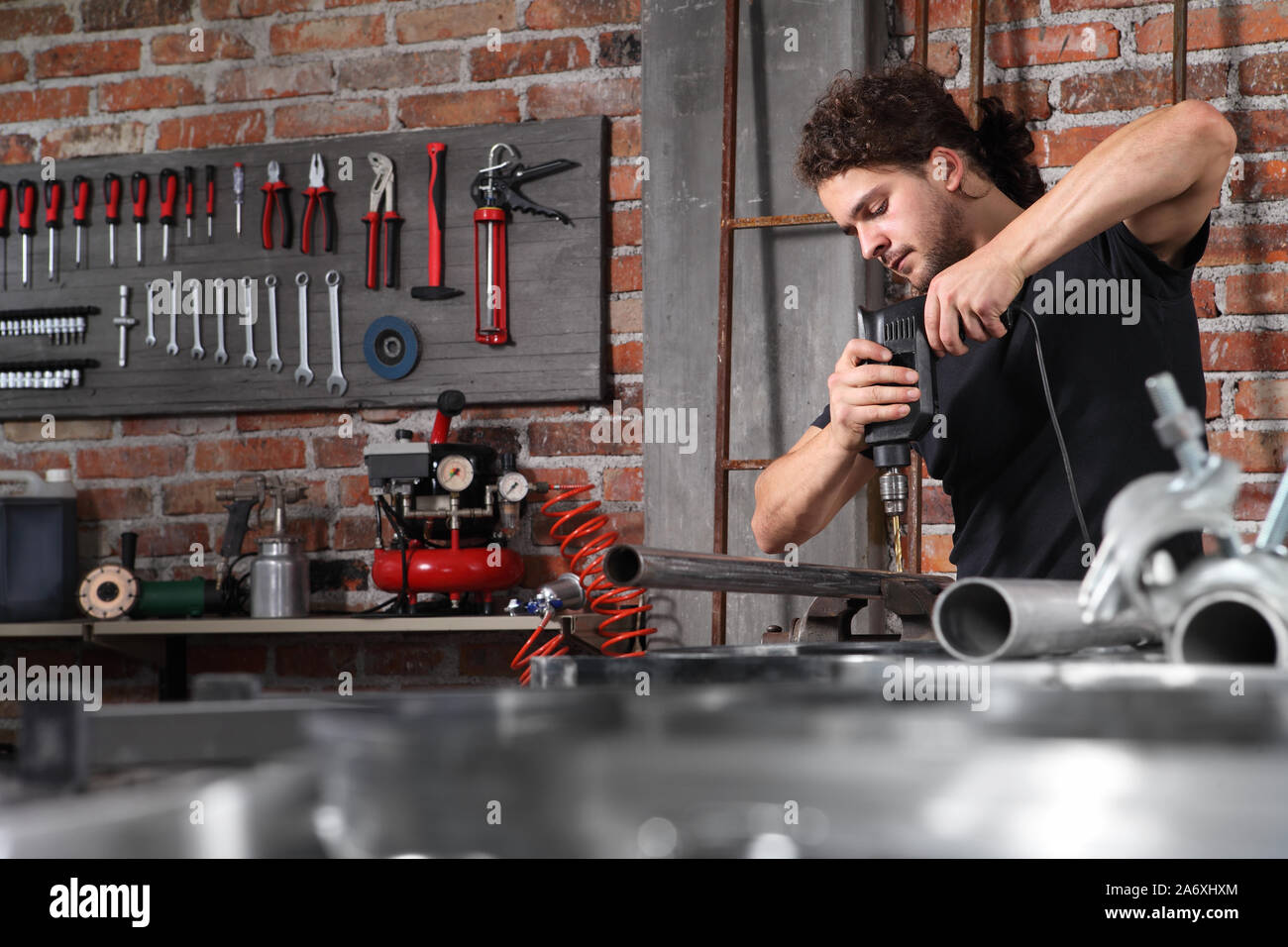 man in home workshop garage work drilling metal with drill, repair iron ...