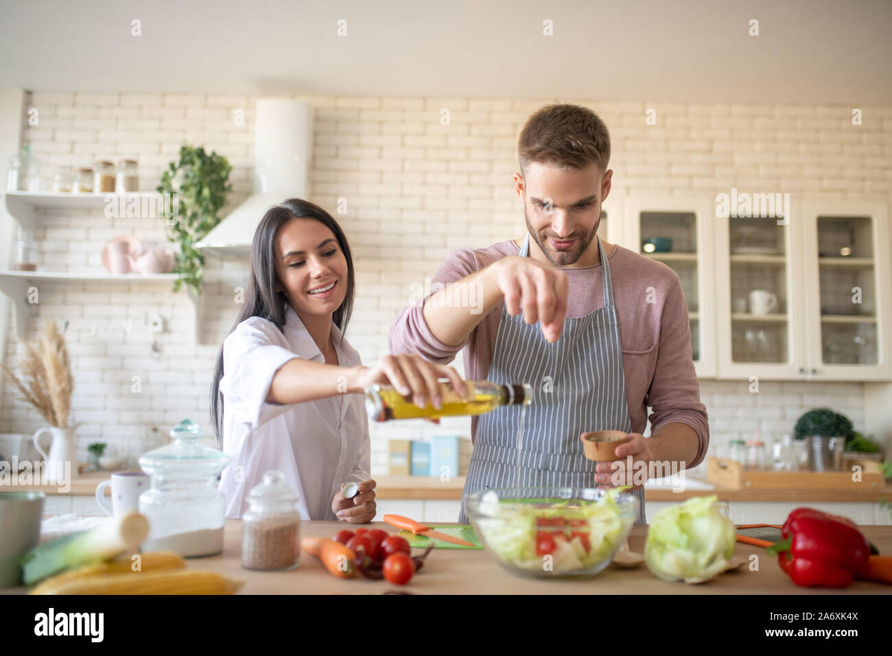 Husband adding spices to salad while cooking with wife Stock Photo - Alamy