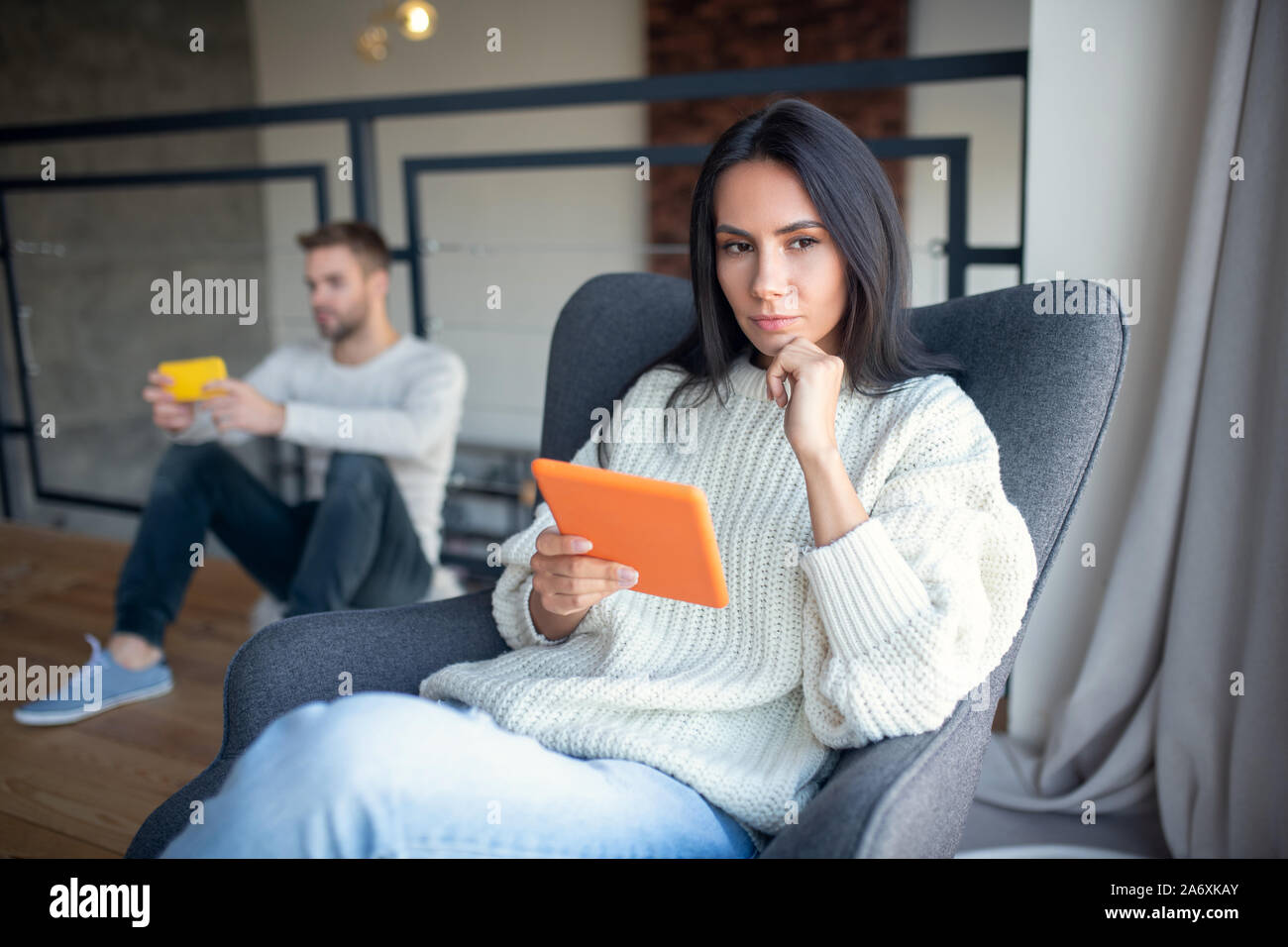 Dark-eyed wife feeling suspicious while husband using phone Stock Photo ...