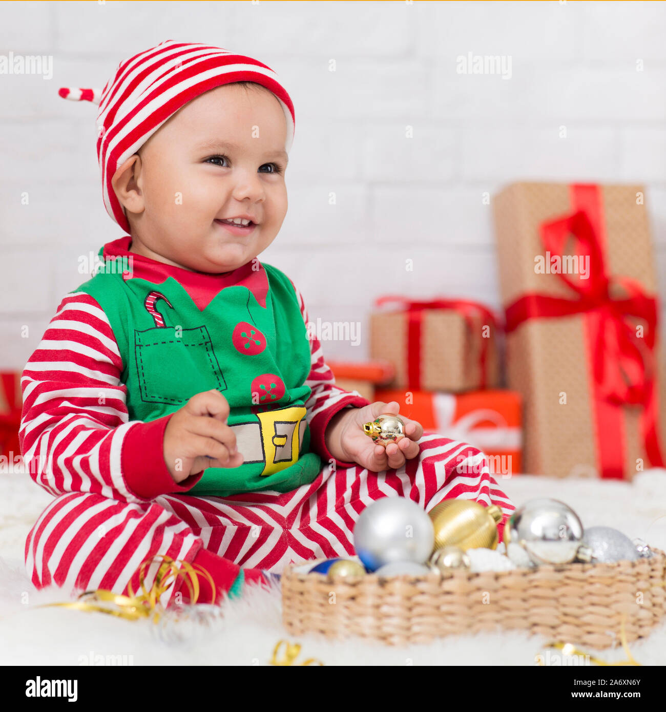 Cute baby elf playing with Xmas decorations Stock Photo - Alamy