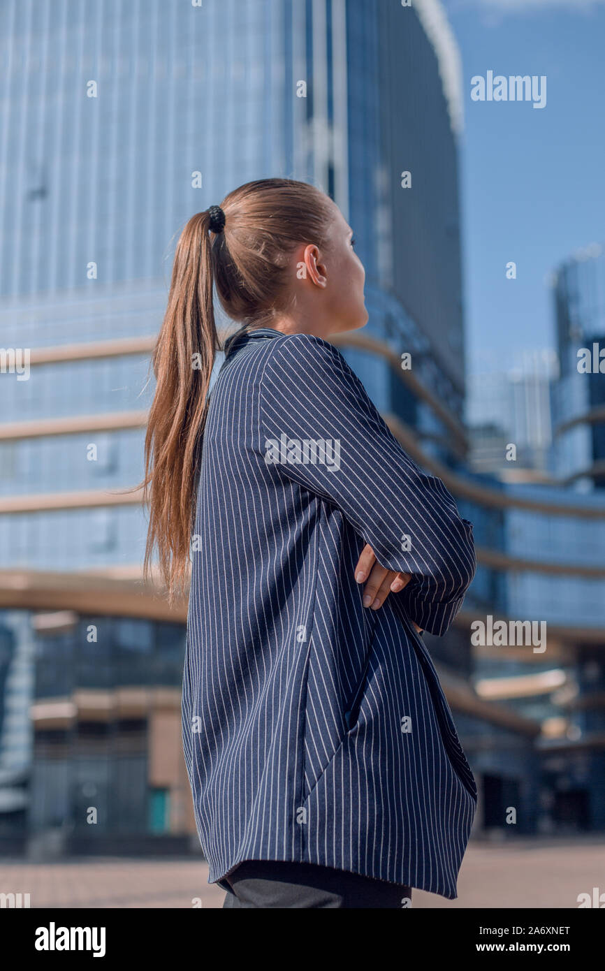 side view. modern young woman standing in front of office building ...