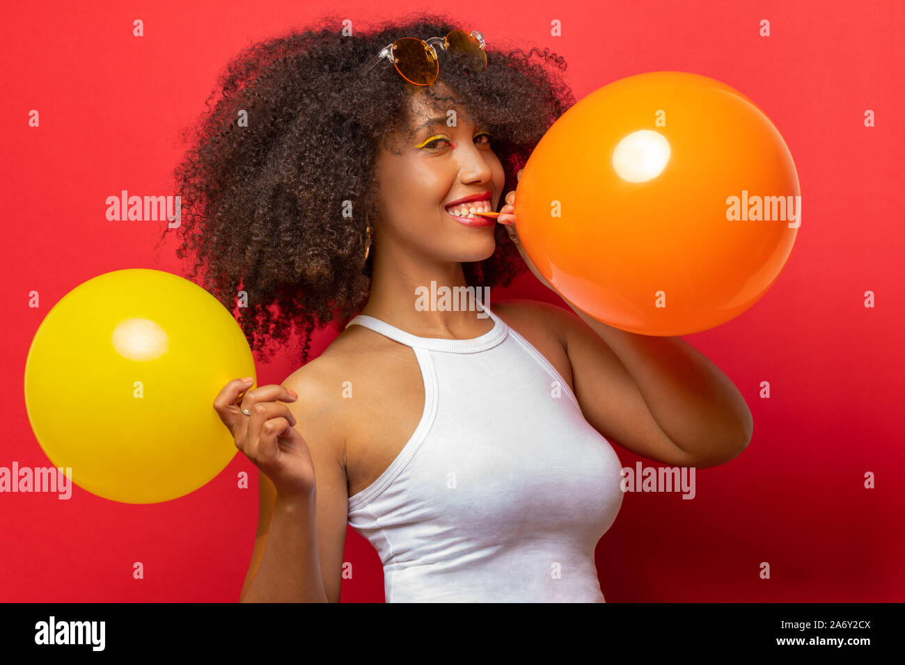 girl with black curly hair inflates two balloons Stock Photo - Alamy
