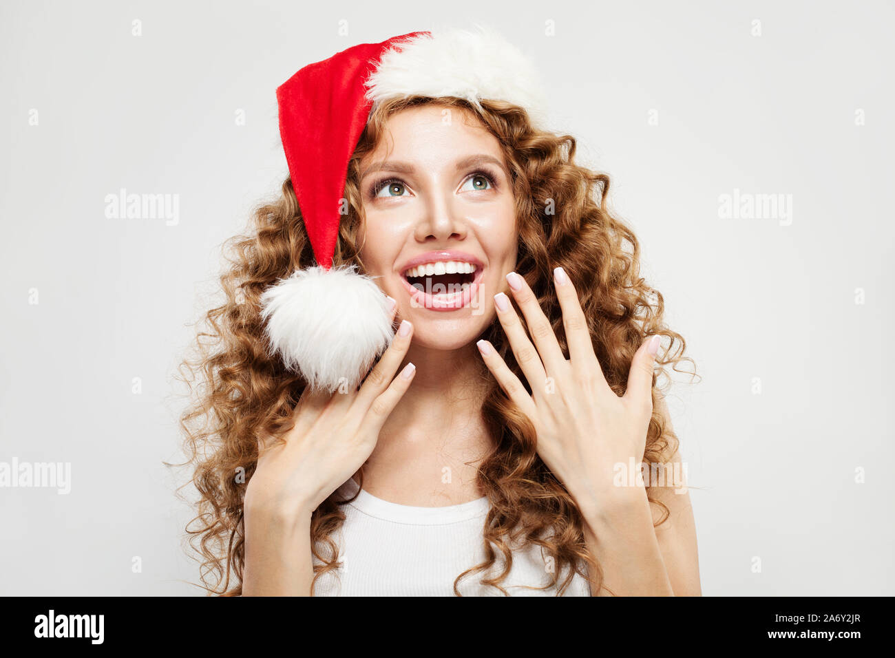 Happy excited surprised young woman in Santa hat smiling. Christmas and New Year party portrait ...