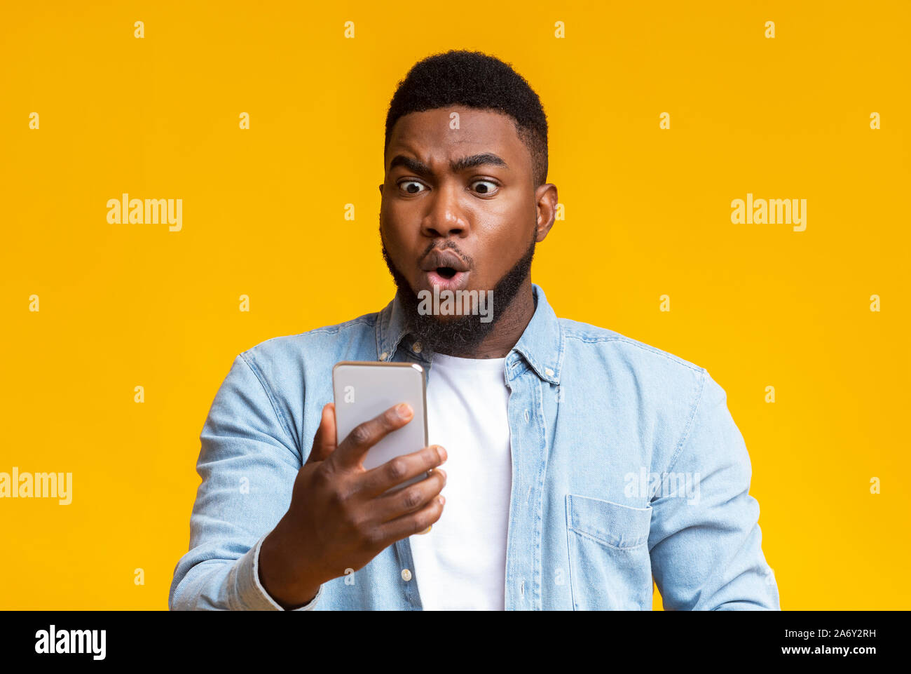 Astonished black guy looking at smartphone screen in shock Stock Photo ...