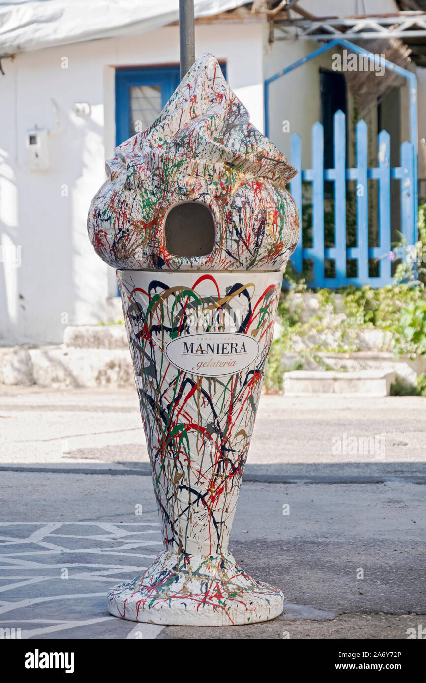 An unusual ornate trash can in the shape of an ice cream cone. Outside ...