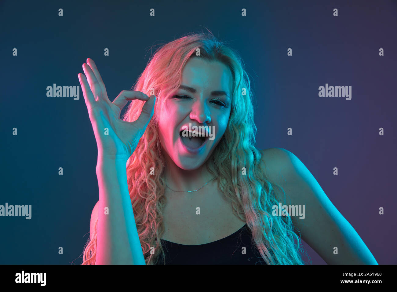 Caucasian young woman's portrait on gradient background in neon light ...