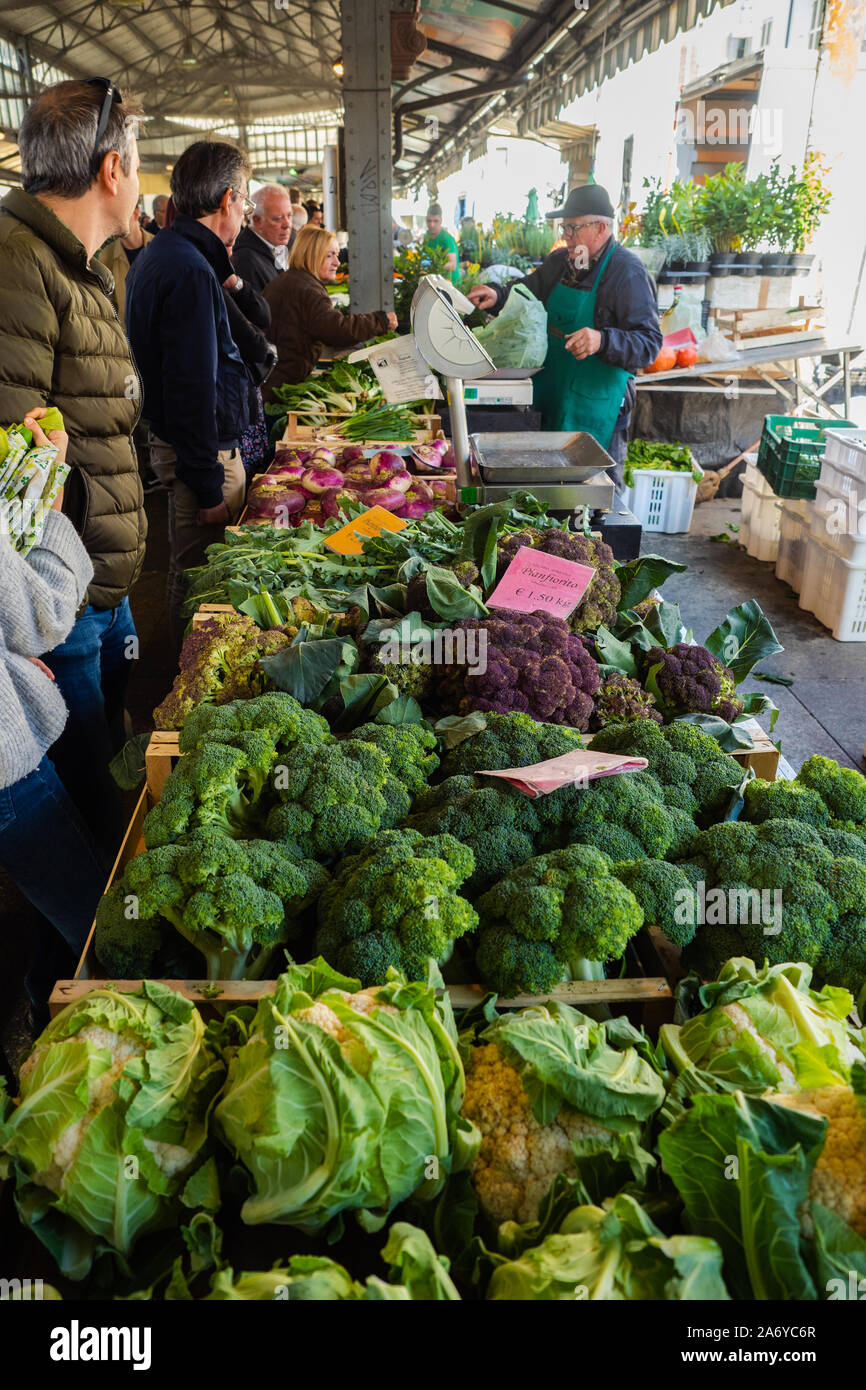 Vegetable seller weighs order while people wait in line to order in ...