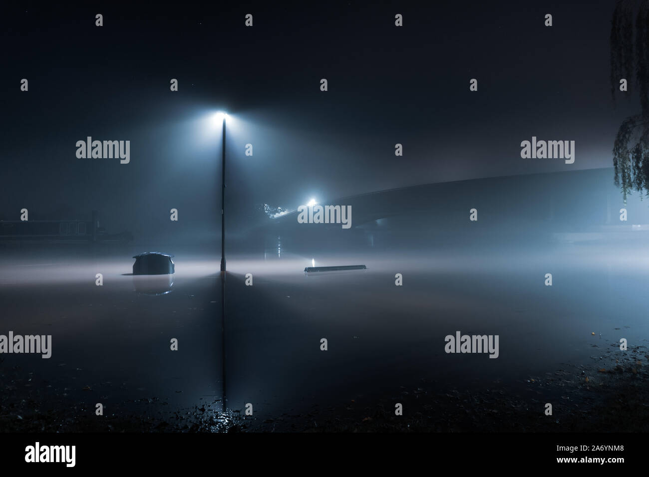 A street light standing in flood water with a brdge behind on a spooky ...