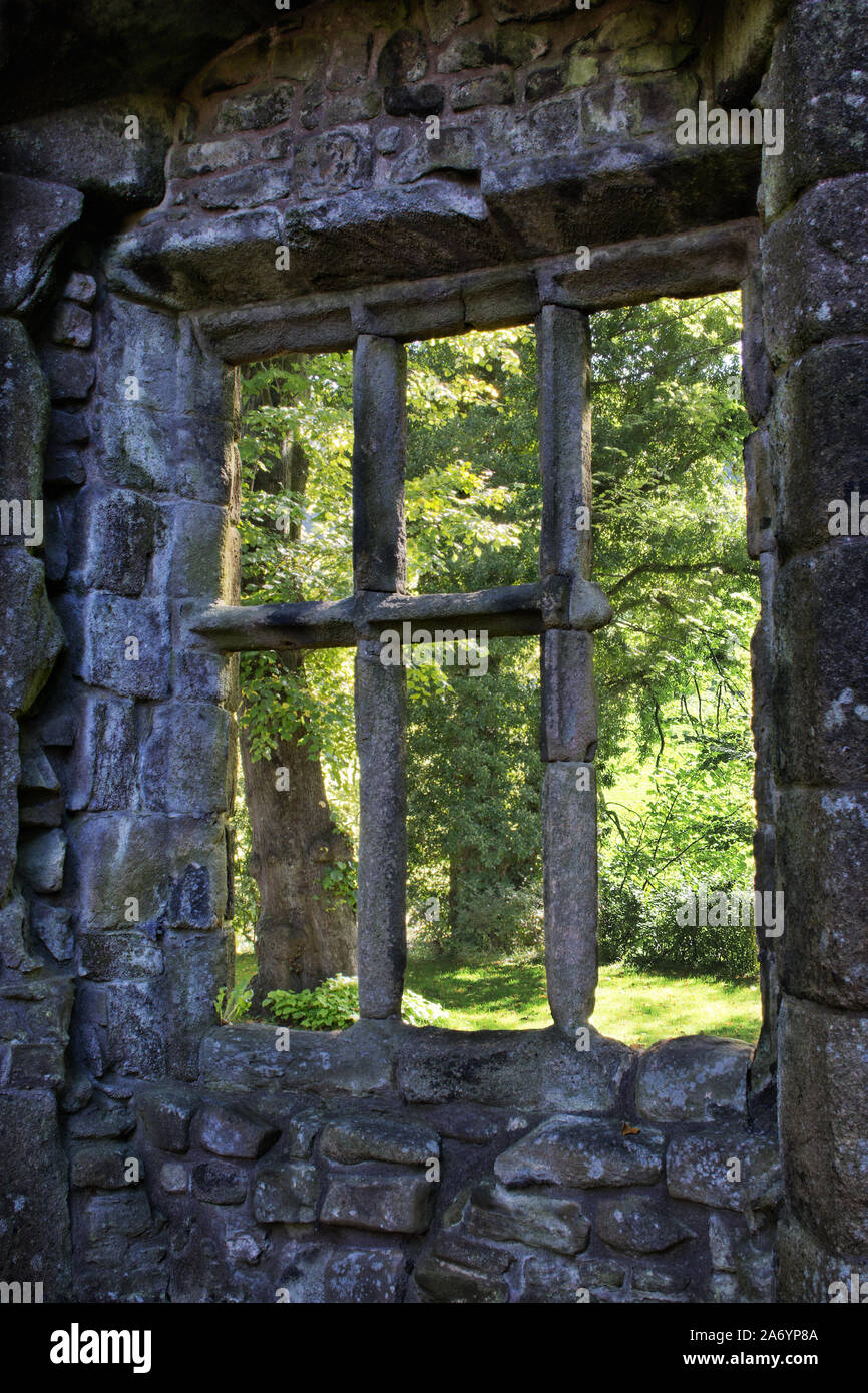 A woodland view from a stone window in the ruins of Whalley Abbey Stock ...