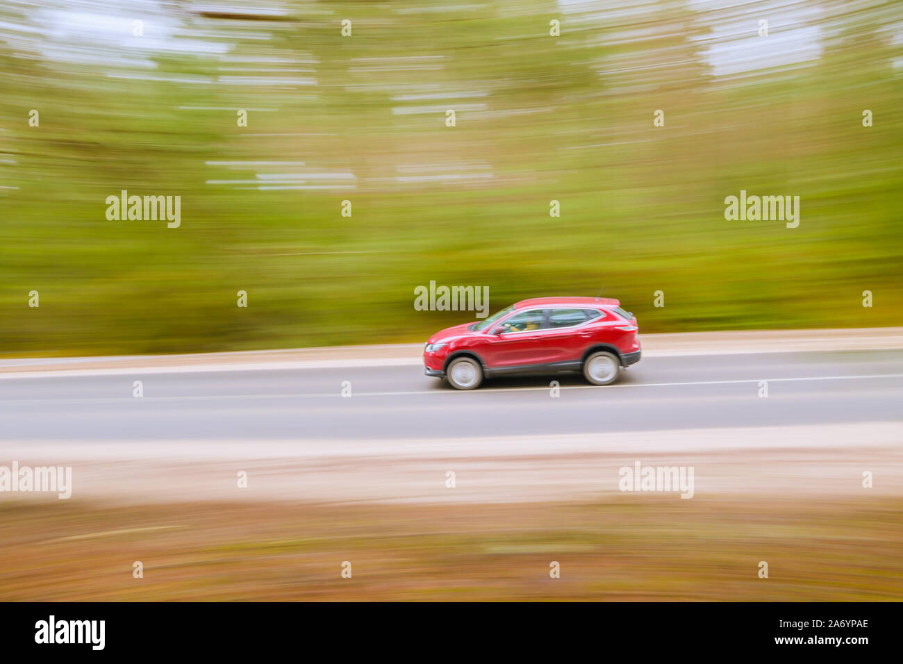 Fast moving red car on asphalt road. Panoramic shot, blurred background ...