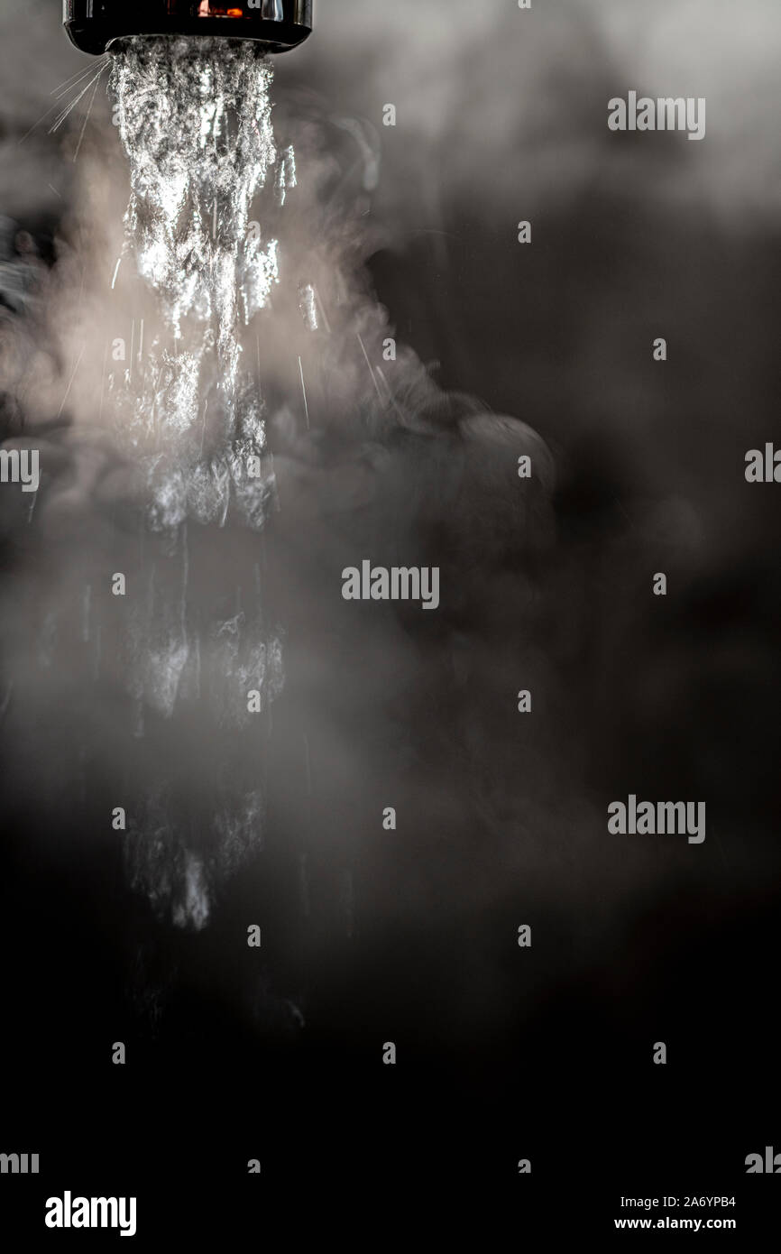 Close up of boiling water flowing from a tap with mists of water vapour ...