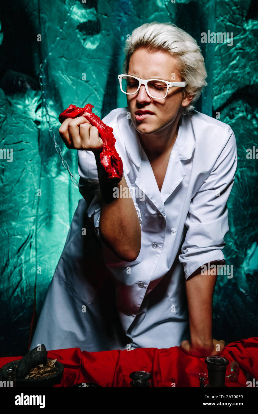 mad medical scientist in doctor's robe eats raw meat and enjoys ...