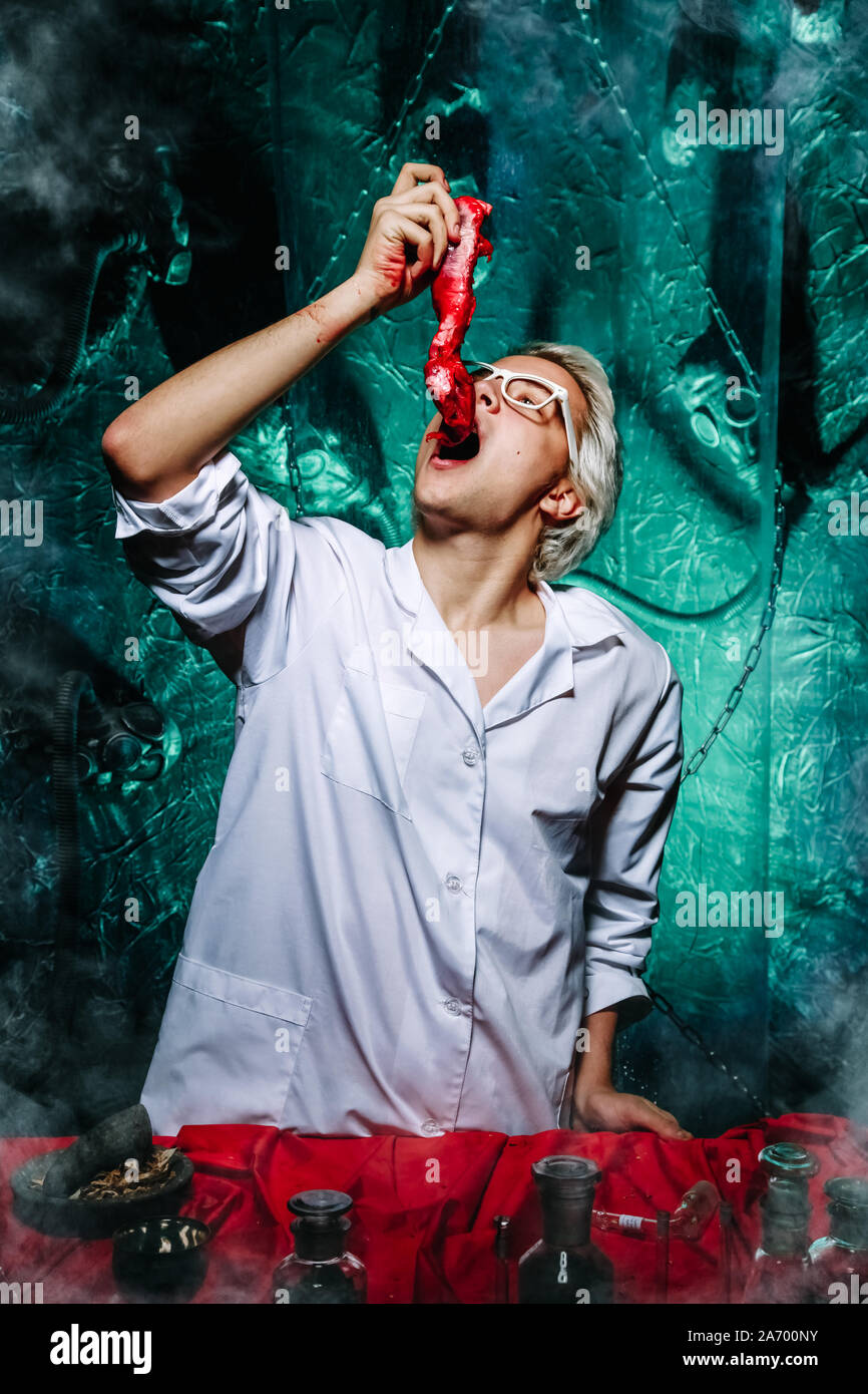 mad medical scientist in doctor's robe eats raw meat and enjoys ...