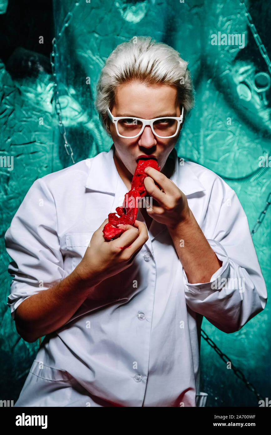 mad medical scientist in doctor's robe eats raw meat and enjoys ...