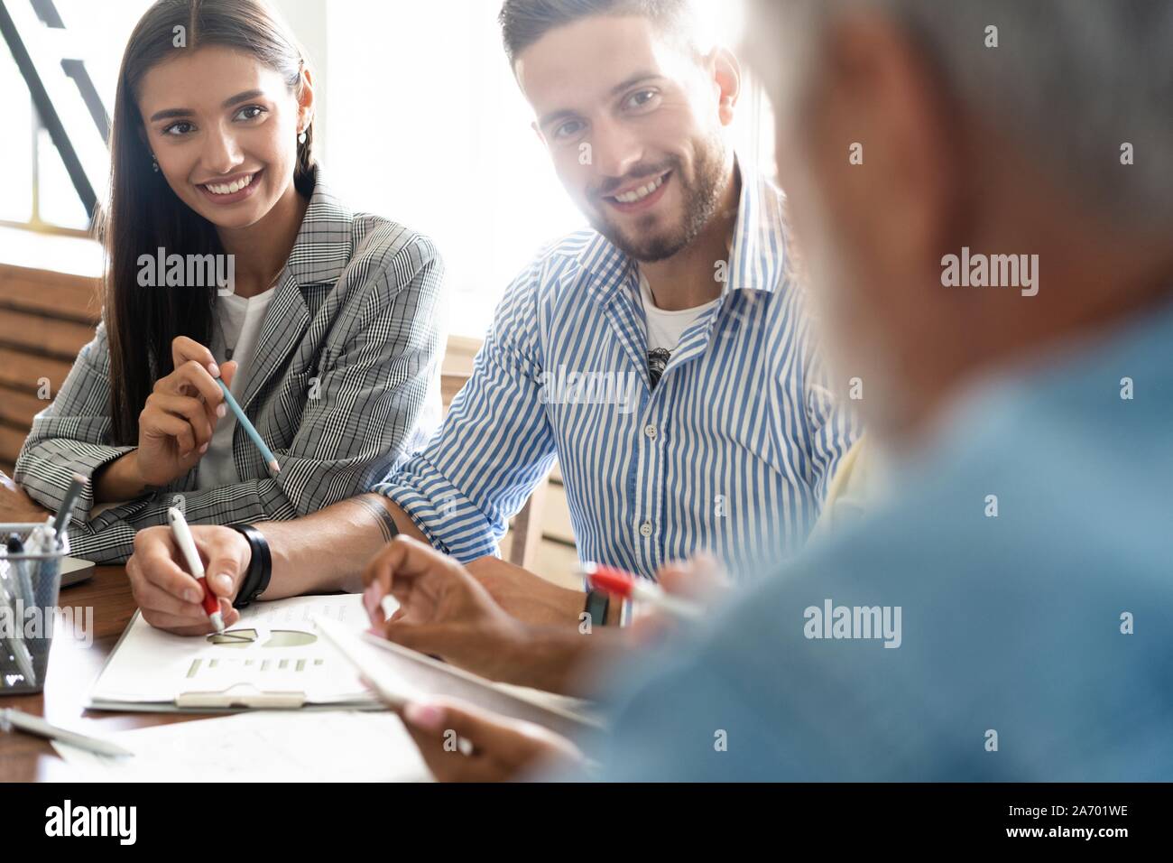 Group of young business people working and communicating while sitting ...