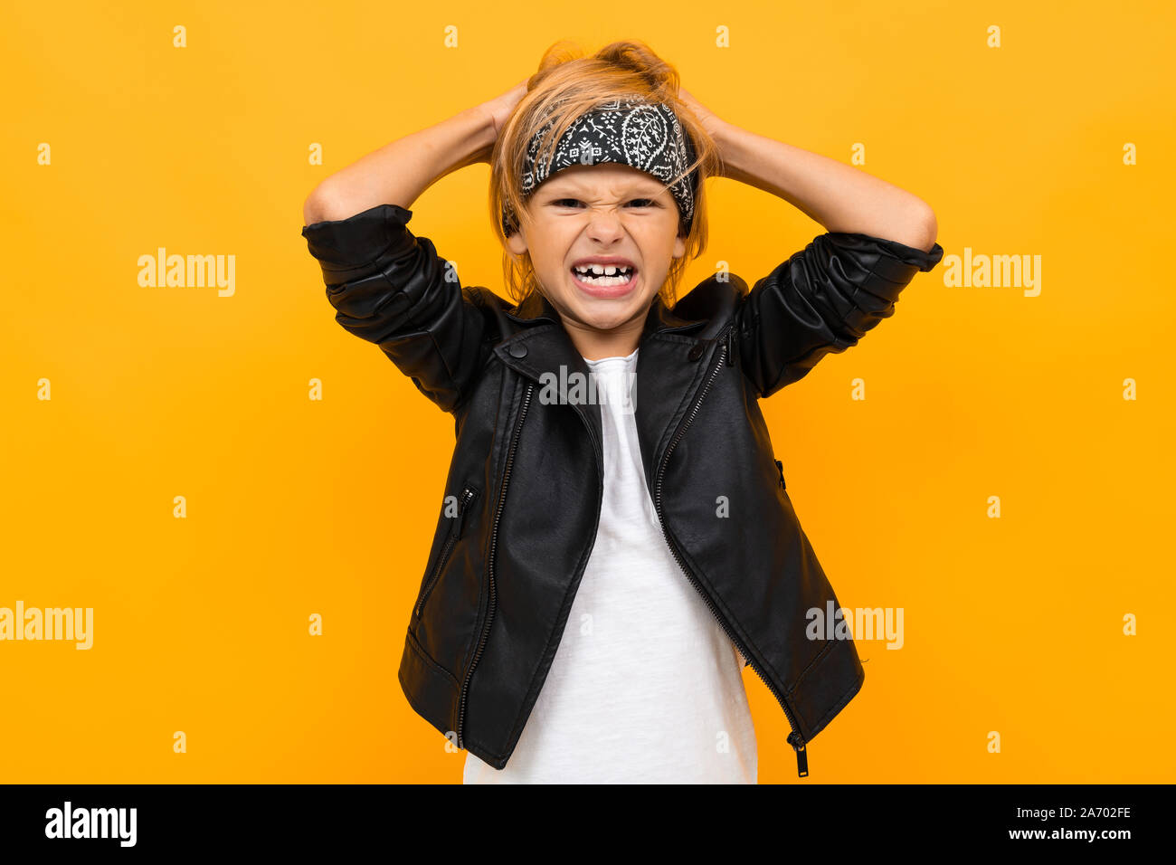 upset boy bully rips his hair, a boy in a black jacket on an orange ...