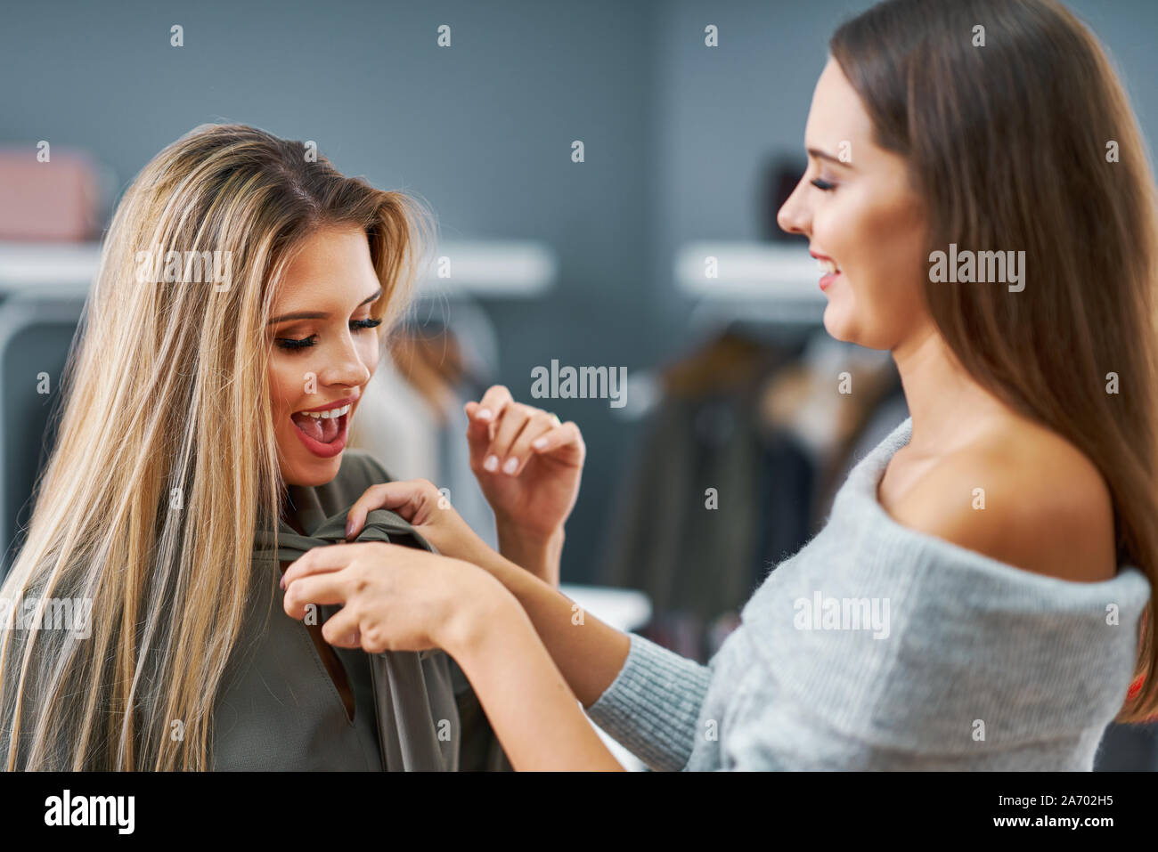 Shop assistant helping customer in boutique Stock Photo - Alamy