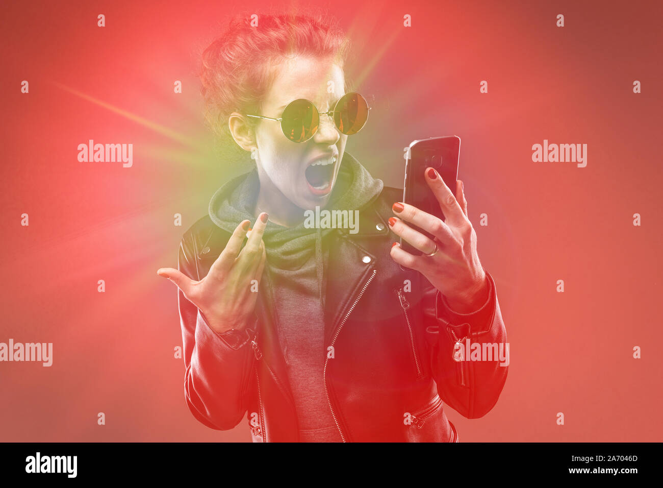 charismatic punk girl in a black jacket with a phone in her hands is ...