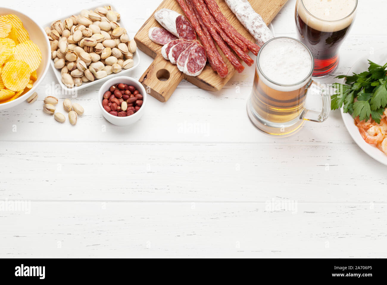 Draft beer and snacks on wooden background. Nuts, chips, sausages and ...