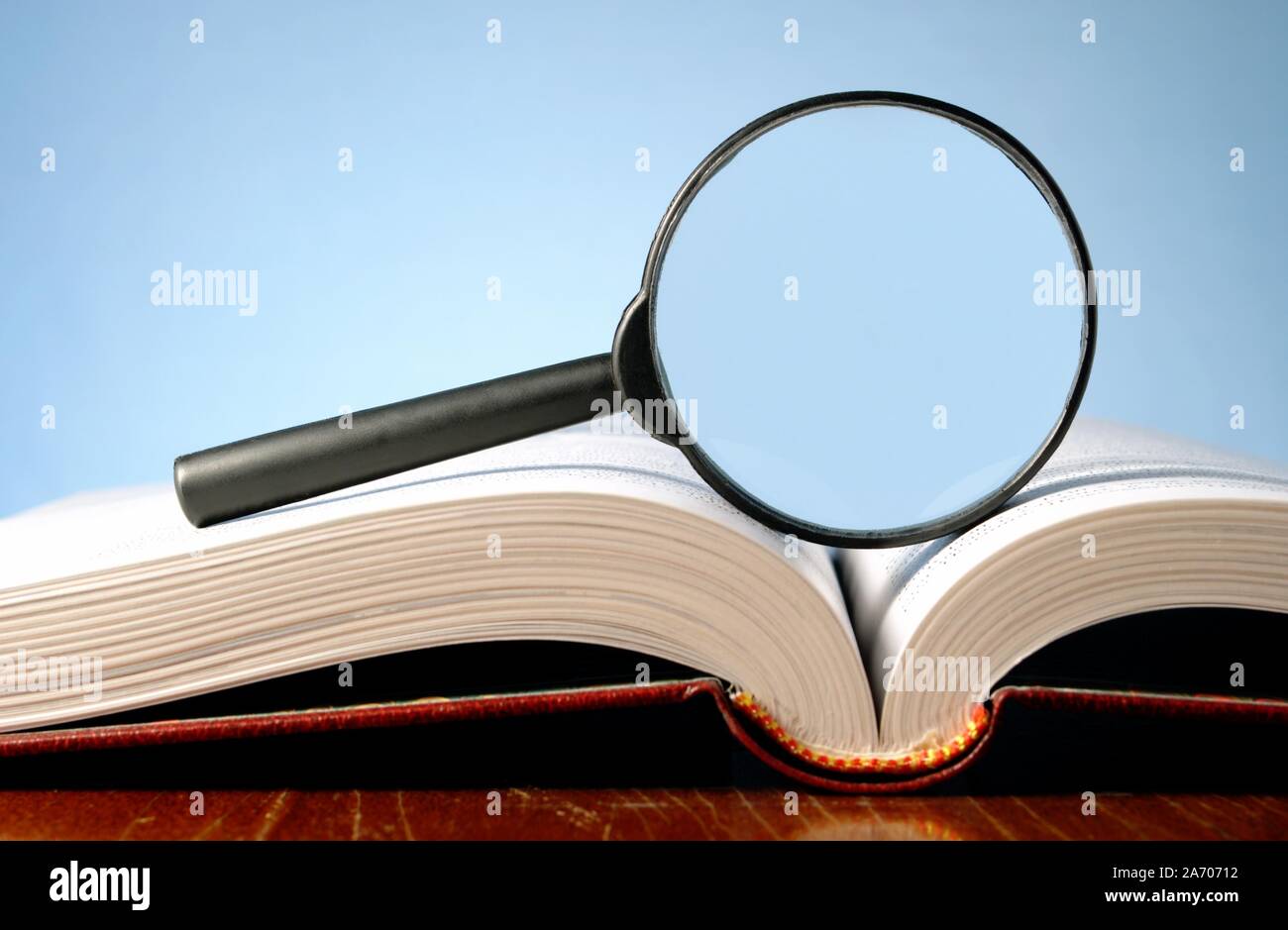 magnifying glass and an open book on a table Stock Photo - Alamy