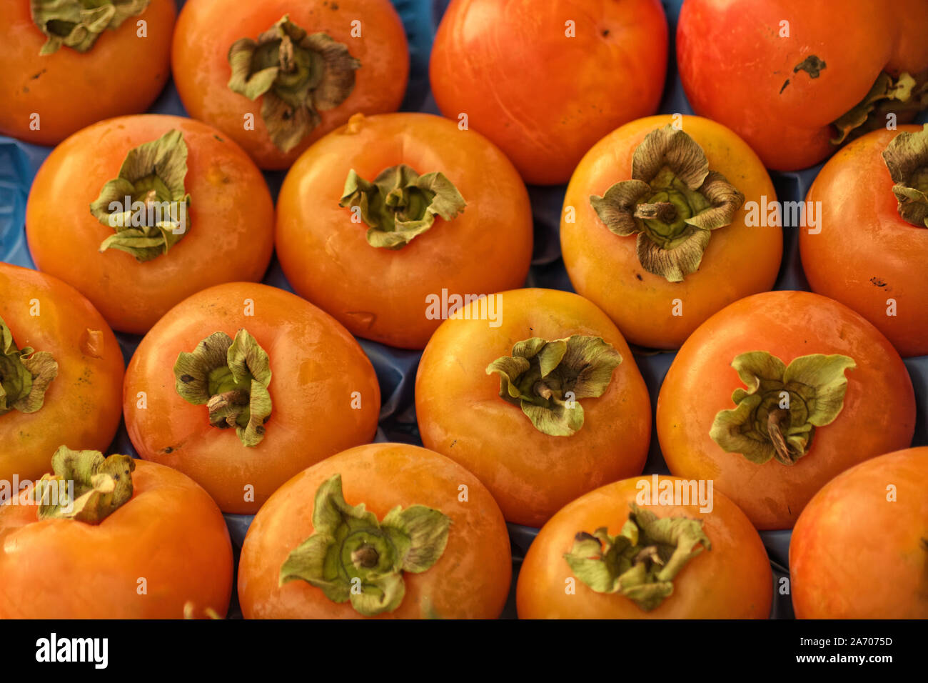 Bunch of ripe asian persimmons on grocery counter Stock Photo - Alamy