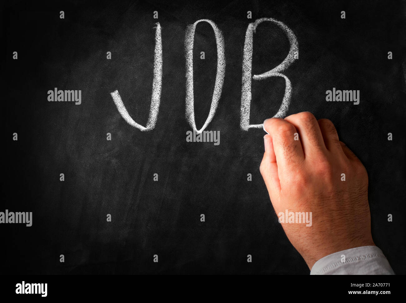 Male hand writing the word Job in capital letters on a black chalkboard ...