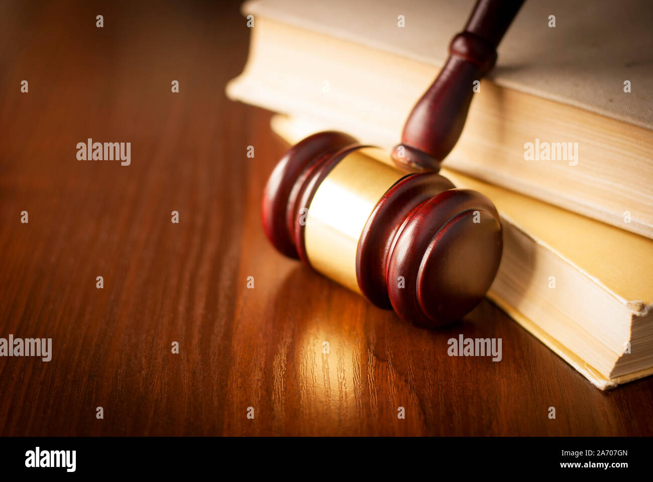Wooden gavel in a courtroom standing upright against a stack of law ...