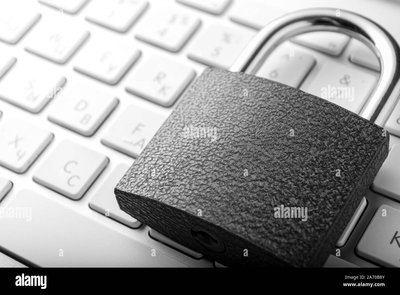 Padlock lying on white computer-keyboard closeup Stock Photo - Alamy