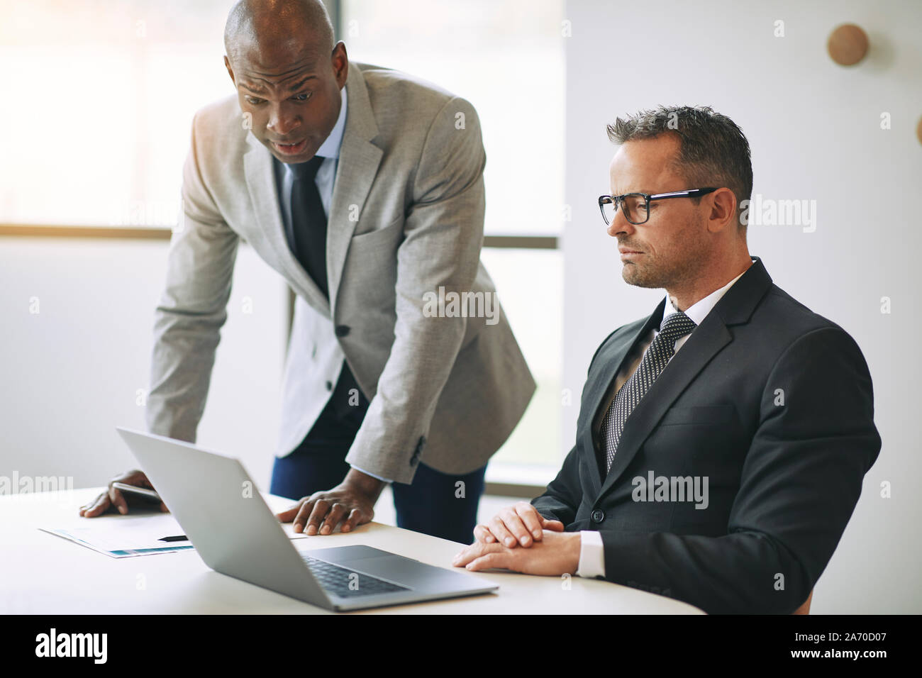 Two diverse businessmen discussing work together while using a laptop ...