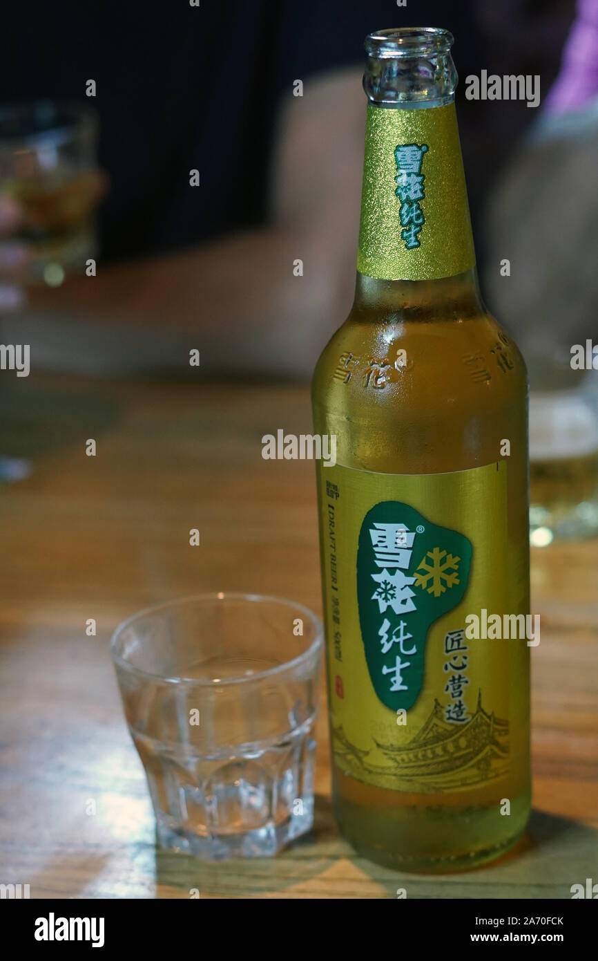 Transparent bottle of Tsingtao beer with gold-green label and half-full ...
