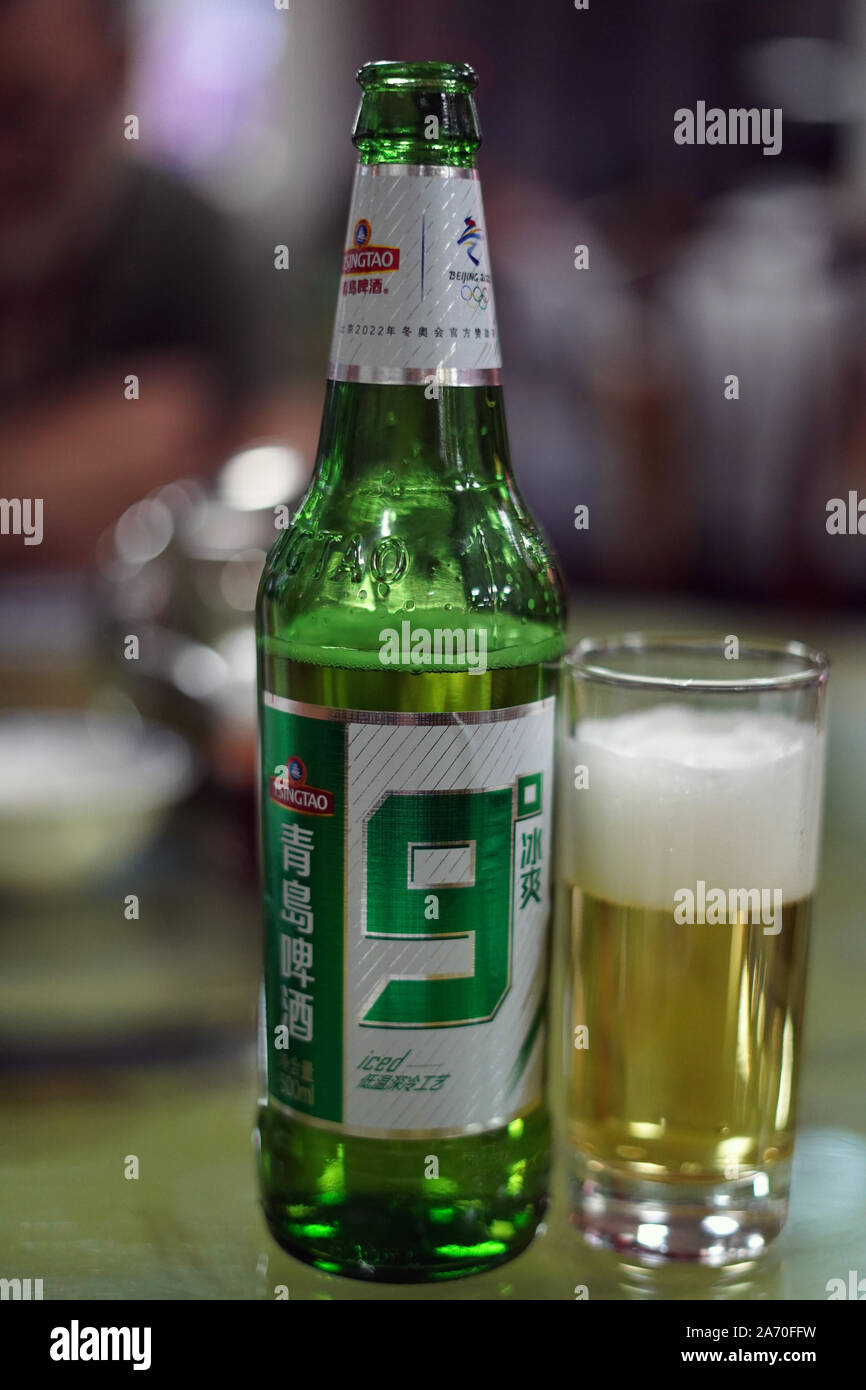 Tsingtao beer number 9 in a green bottle with half-filled tall glass of ...