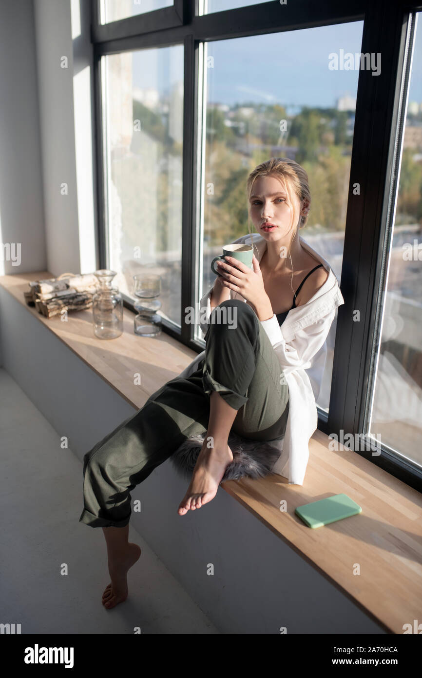 Blonde woman sitting near window in the morning Stock Photo - Alamy