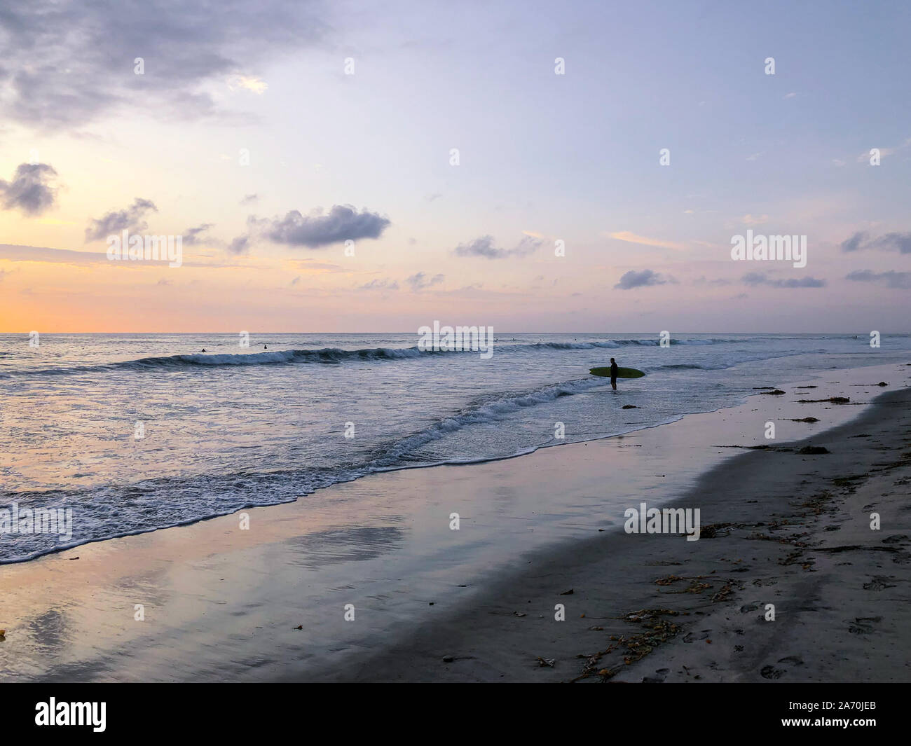 Silhouette of surfer with his board on the beach at Sunset. A man is ...