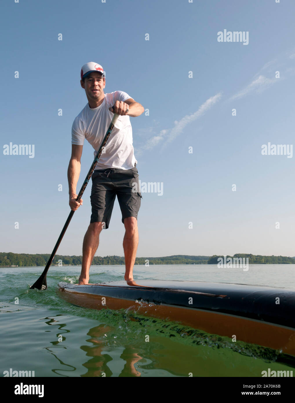 Sporty man doing a morning workout with SUP board on a beautiful lake ...