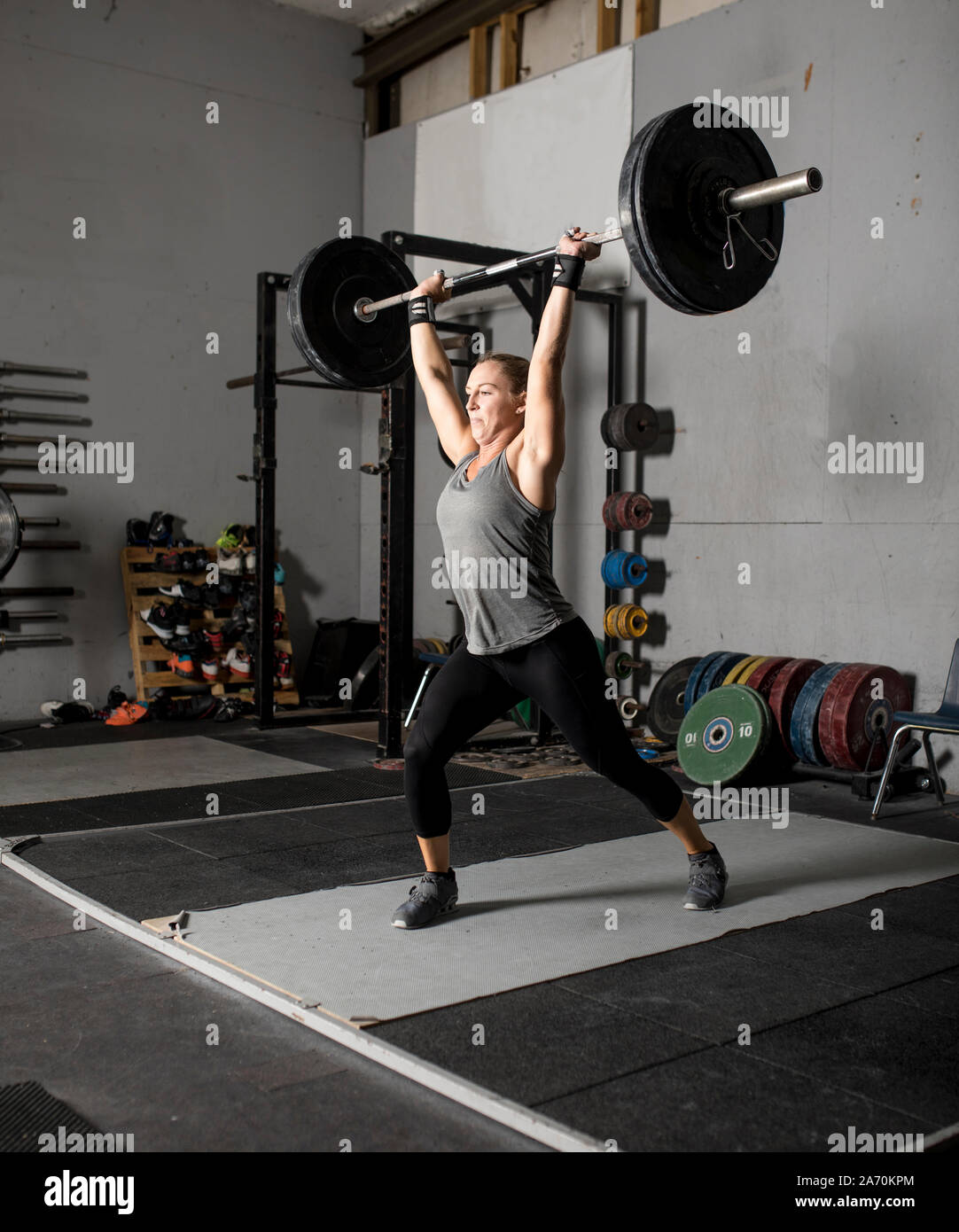 Strong femal weight lifter with heavy weights over her head, two thirds ...
