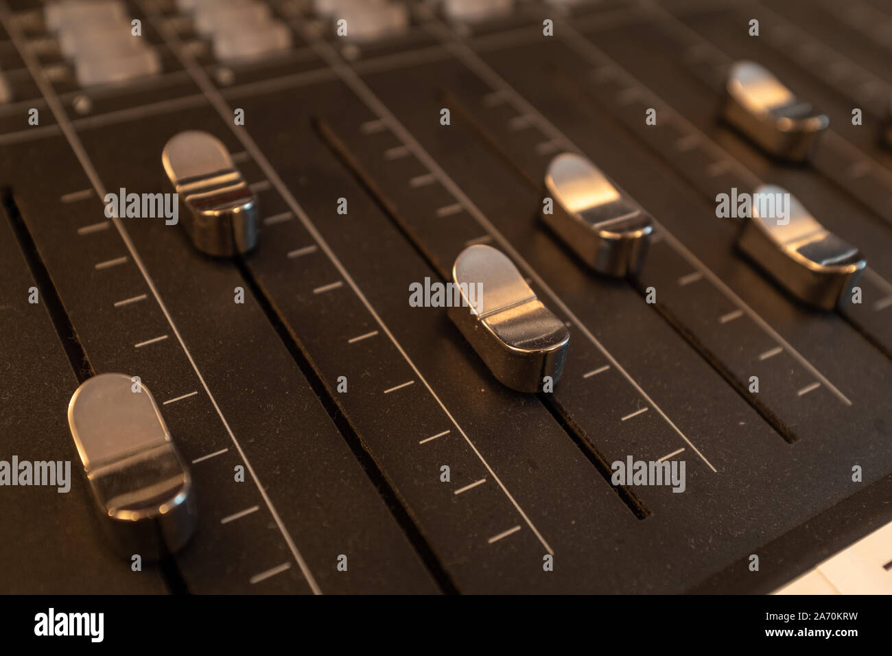 A close up of silver-coloured sliders on a mixing desk in a music ...
