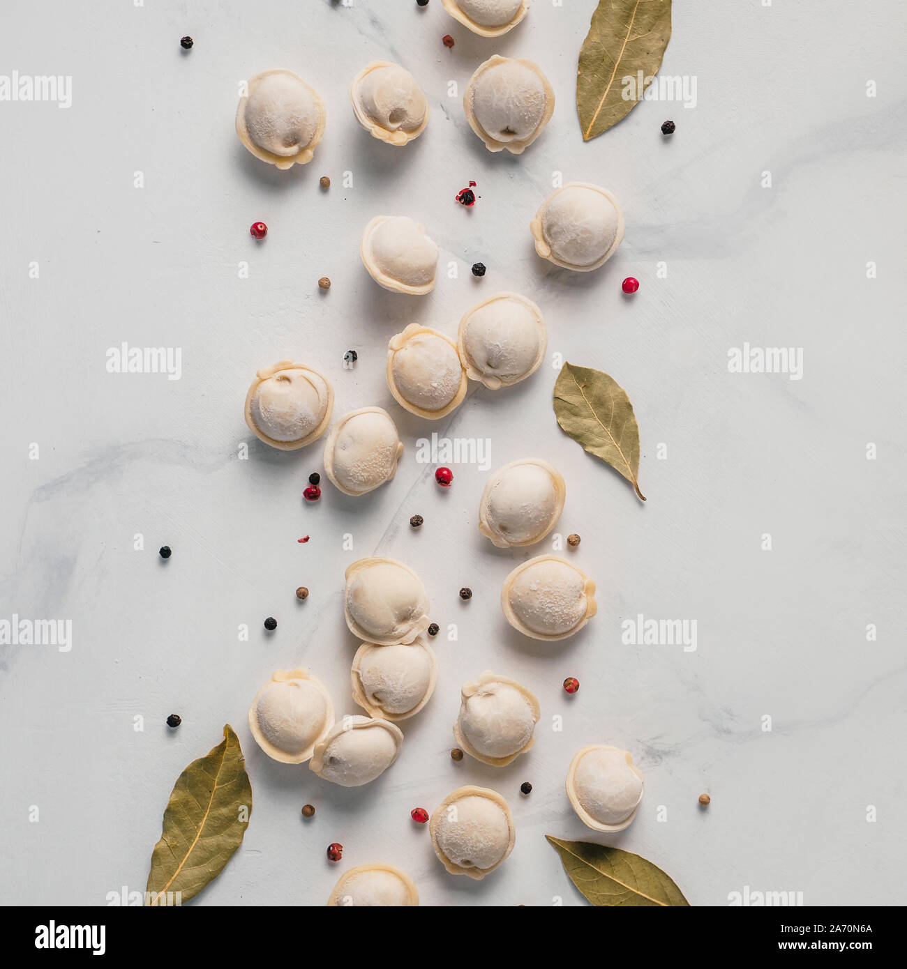 Pattern of frozen uncooked russian pelmeni with peppercorns and bay ...