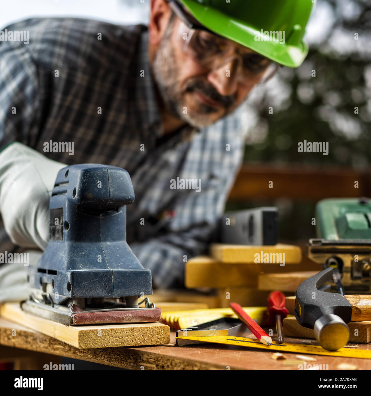 Adult carpenter craftsman wears protective leather gloves, with the ...