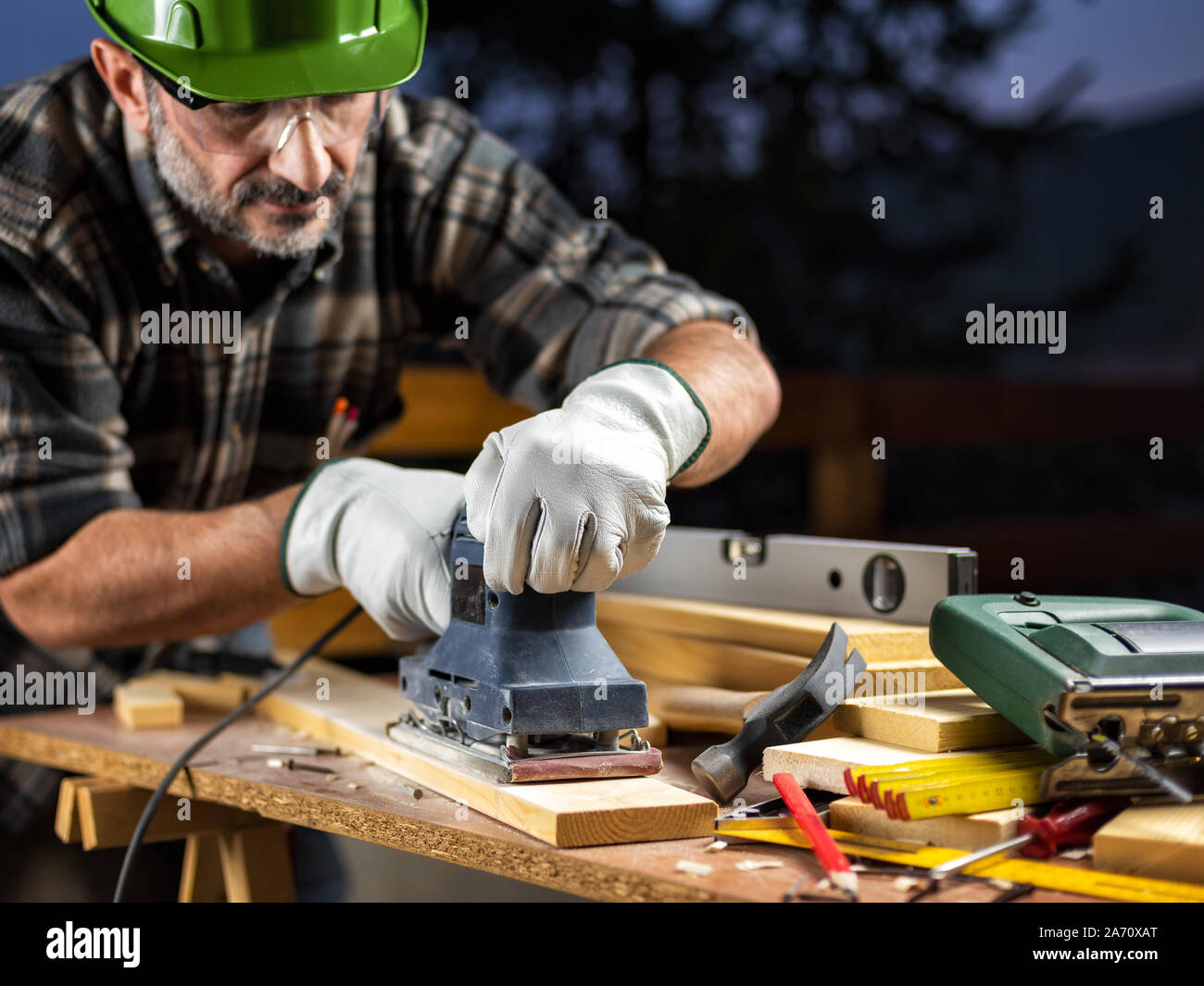 Adult carpenter craftsman wears protective leather gloves, with the ...