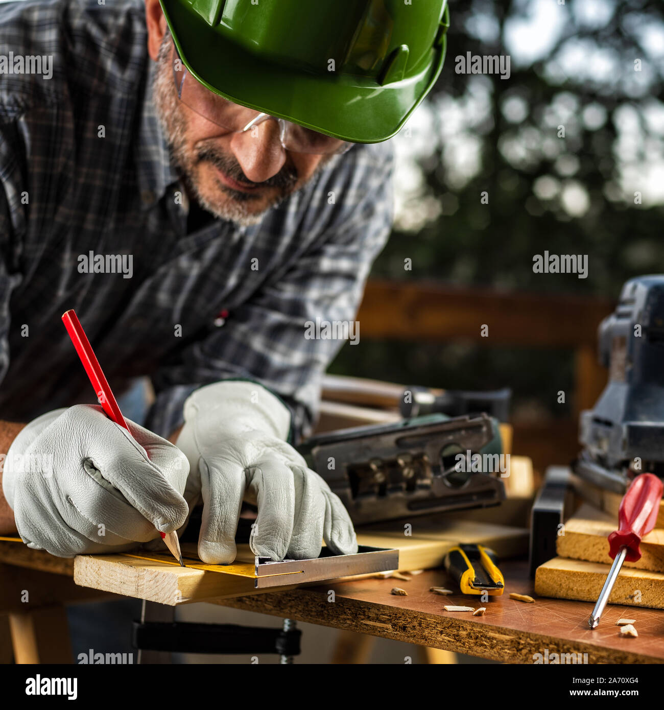 Adult carpenter craftsman wearing helmet and protective leather gloves ...
