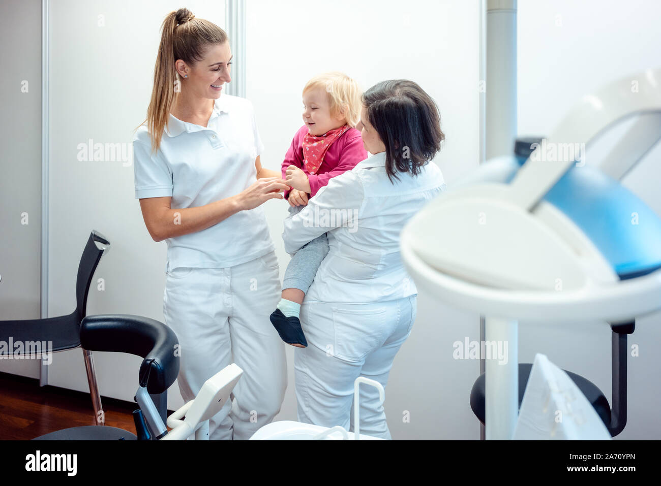 Dentist and her assistant with child in the office Stock Photo - Alamy