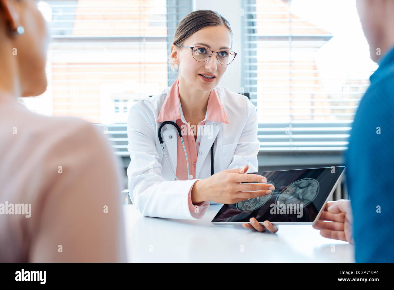 Doctor woman showing patients x-ray pictures on her tablet computer ...